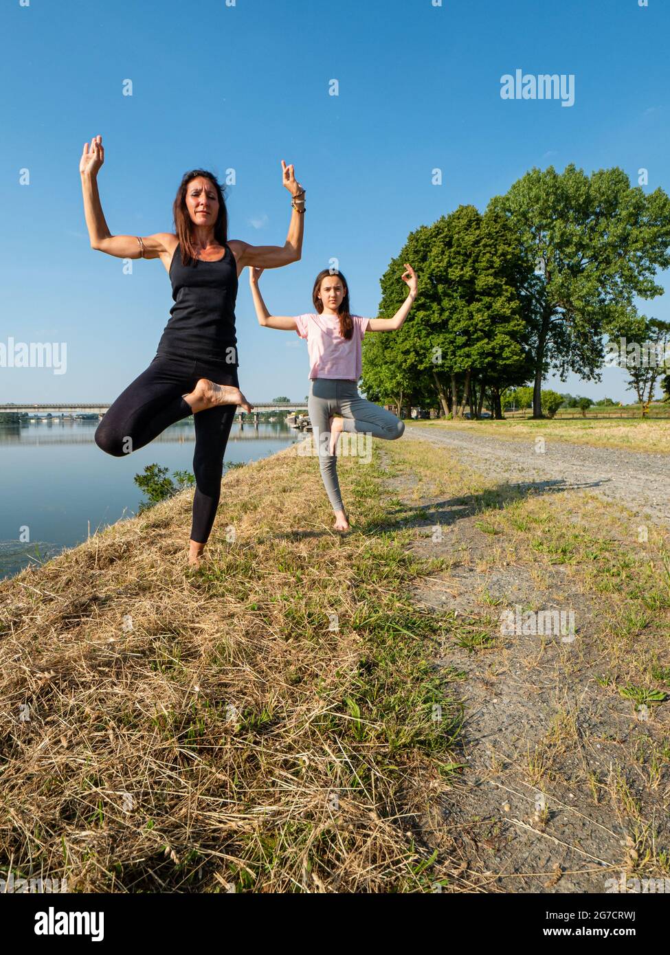 Mother and daughter practicing yoga by the river - healthy lifestyle ...