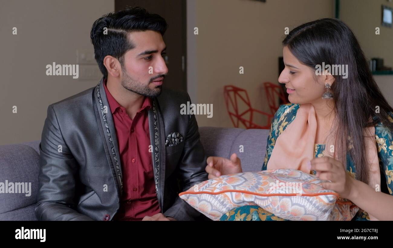 Shallow focus of an Indian man and woman on the couch talking to each ...