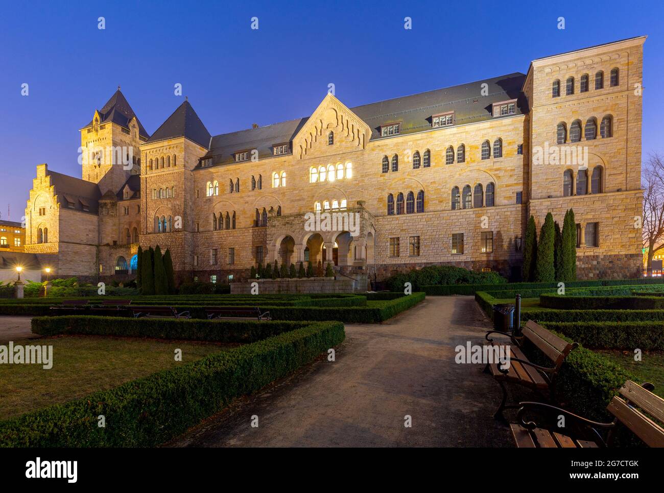 Facade of a beautiful old stone building and public garden at sunset ...