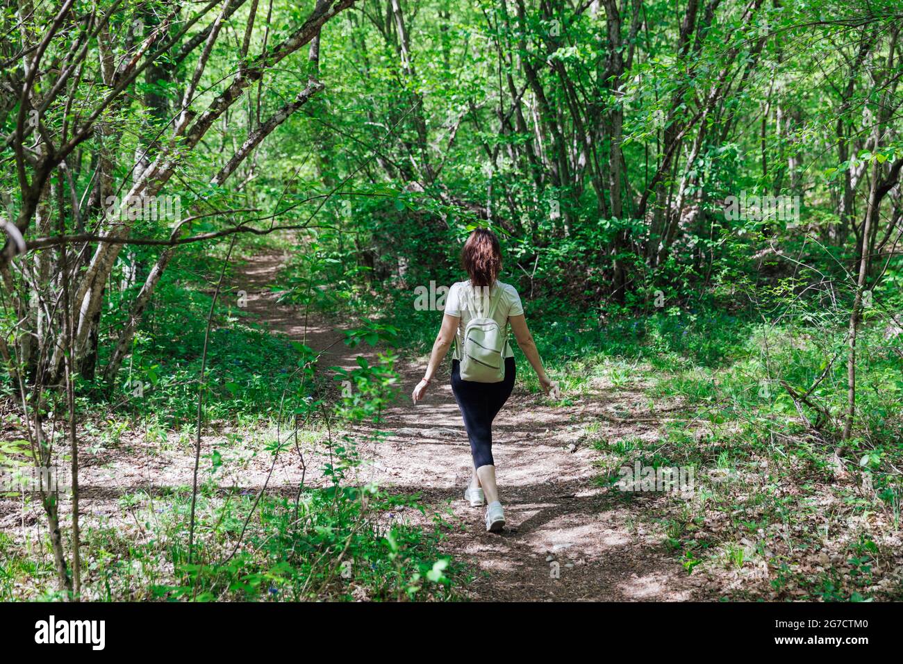 woman walking through the green forest nature journey Stock Photo - Alamy