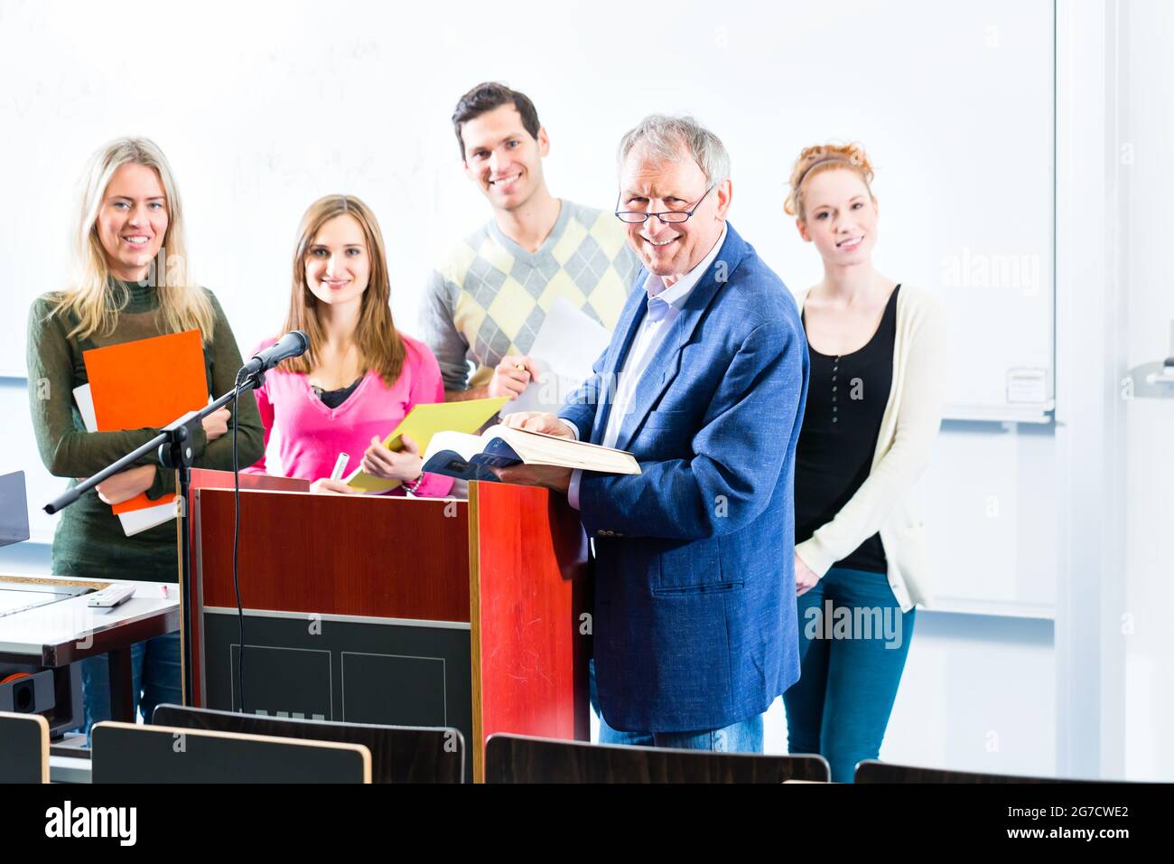 College students making lesson notes while asking professor in ...