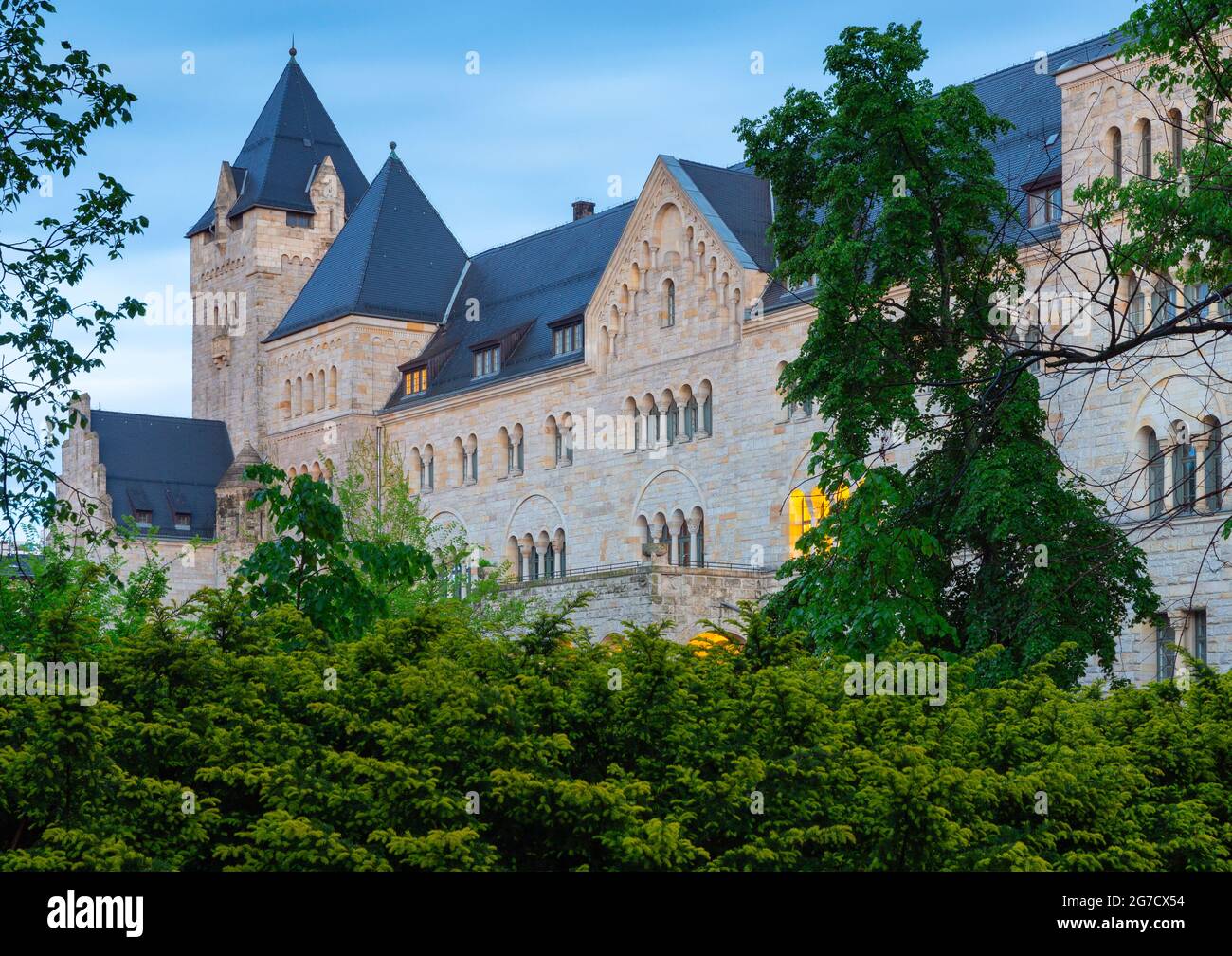 Facade of a beautiful old stone building and public garden at sunset ...