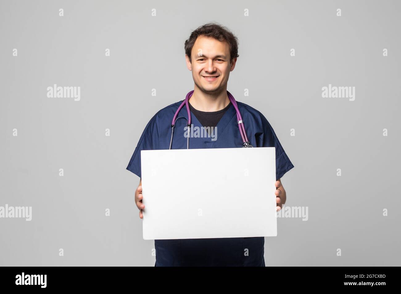 Portrait of a handsome doctor pointing at a blank panel against a white ...