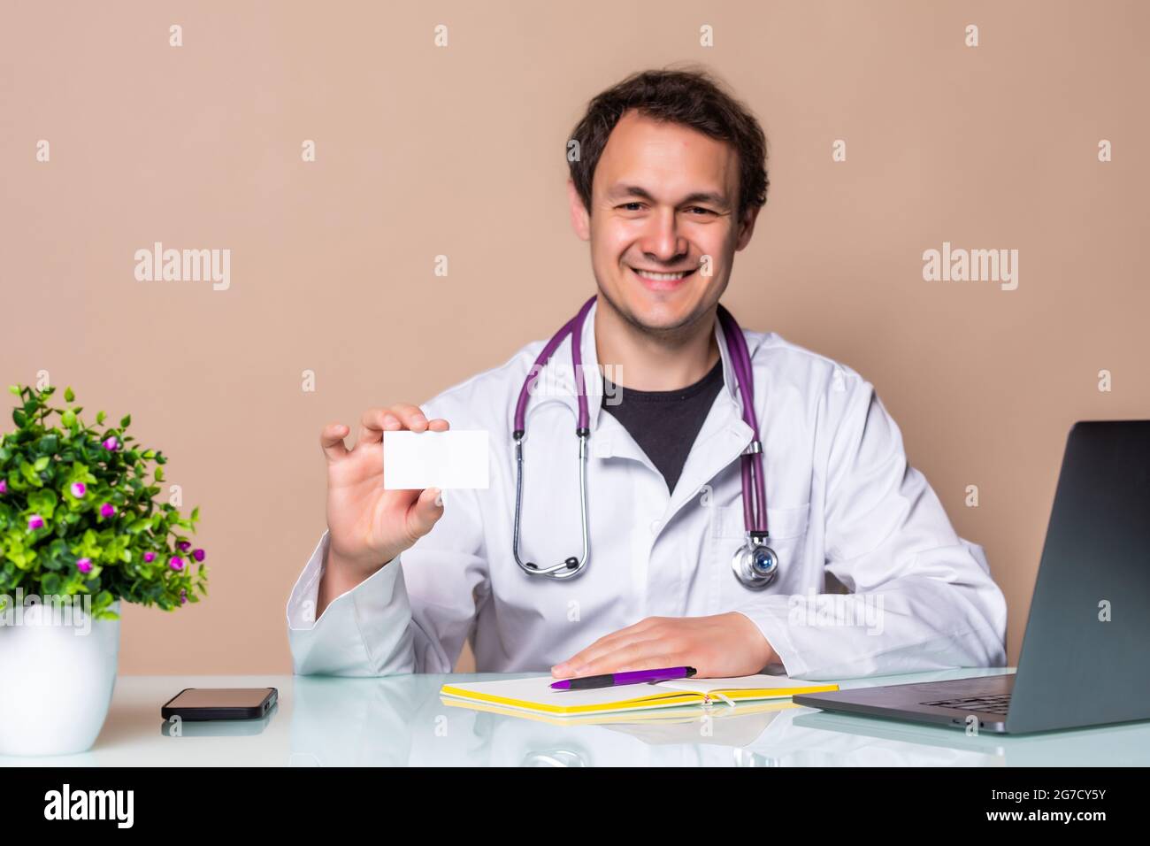 Portrait of successful doctor giving business-card at clinic office ...