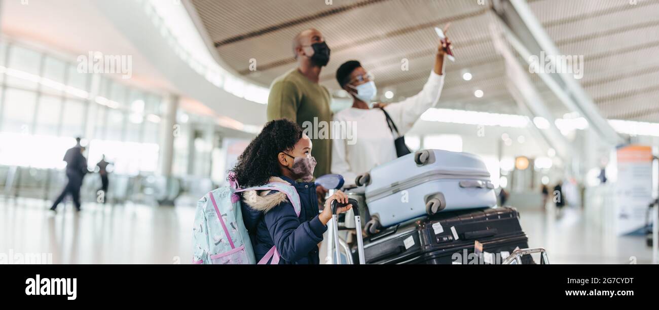 Mother showing something to her family at airport. Young daughter ...