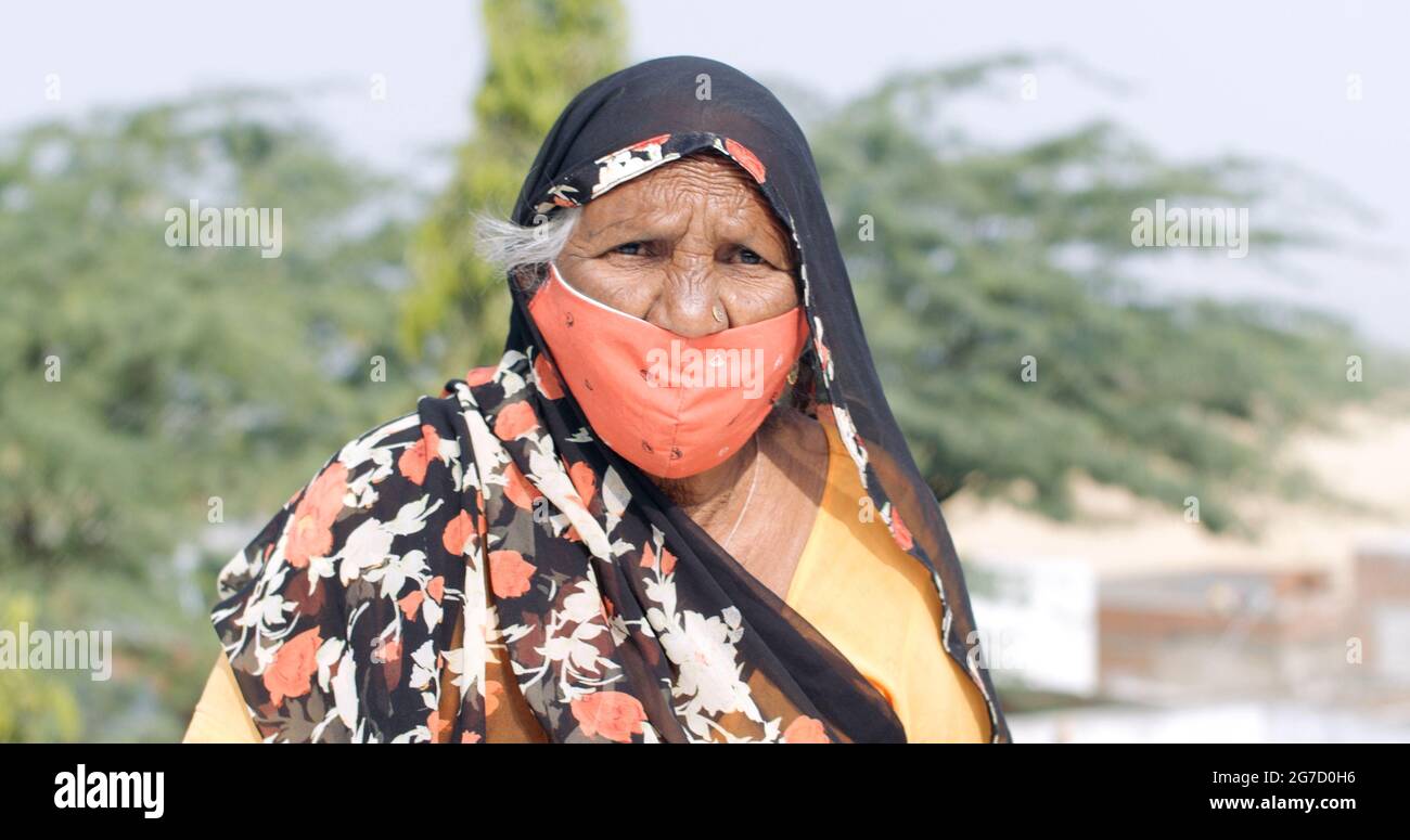 Old Indian woman wearing a traditional sari an face mask- new normal ...