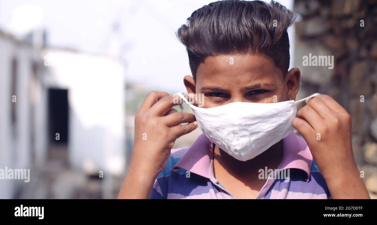 Closeup shot of an Indian boy putting on a mask- new normal concept ...
