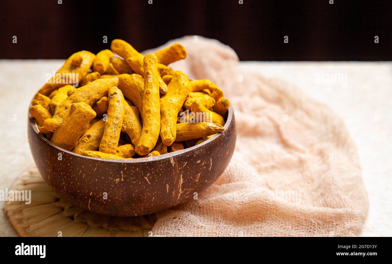 Dried turmeric roots in coconut shell bowl on a light background Stock ...