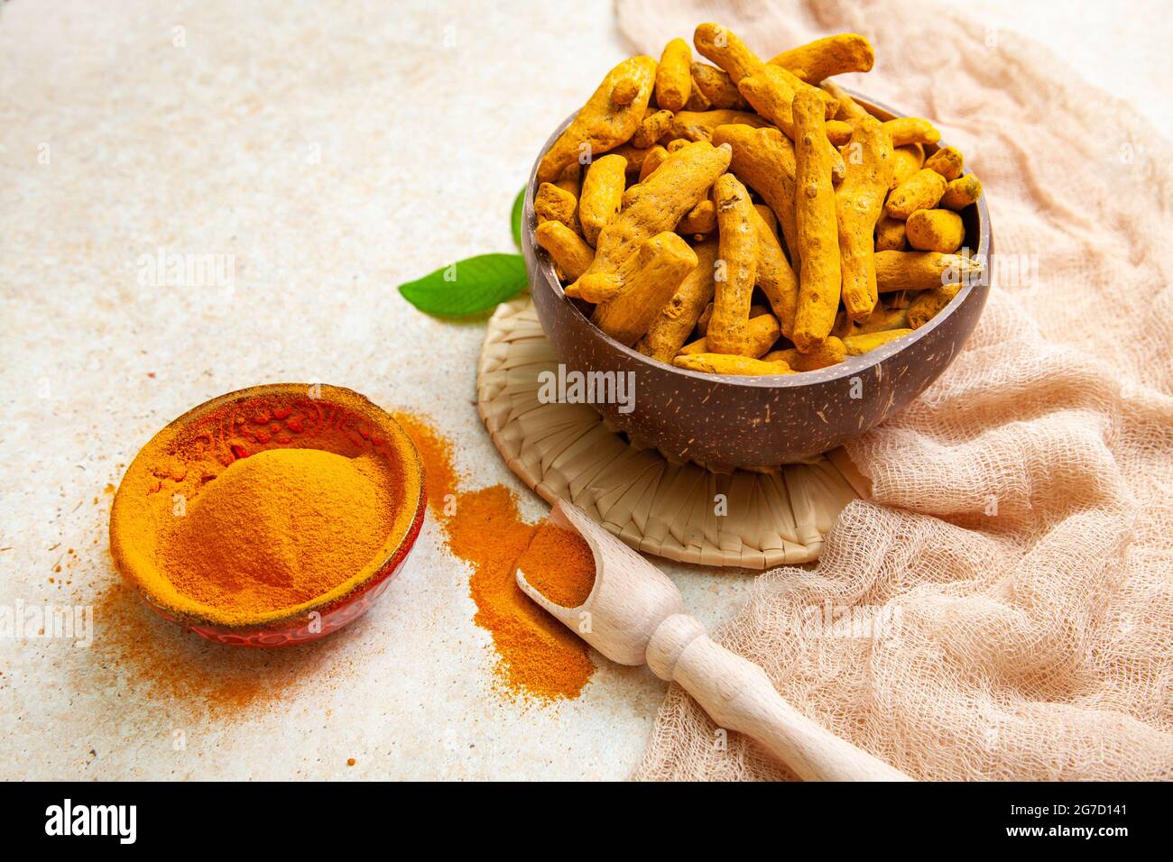 Dried turmeric roots and powder with leaves on a light background Stock ...