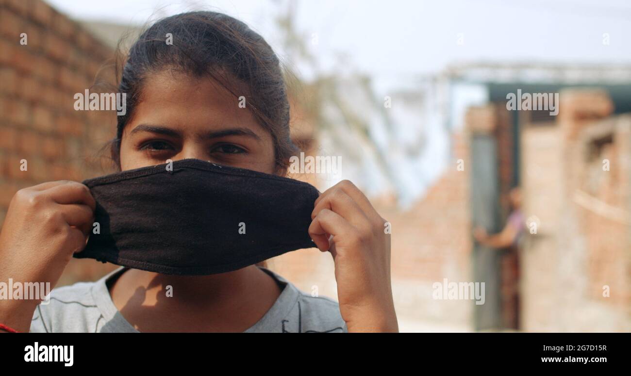 Closeup shot of an Indian girl putting on a mask- new normal concept Stock Photo - Alamy