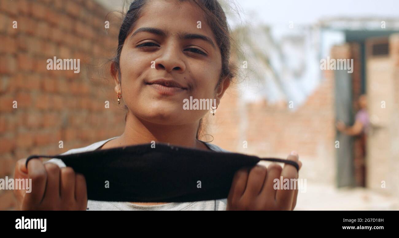 Closeup shot of an Indian girl putting on a mask- new normal concept Stock Photo - Alamy