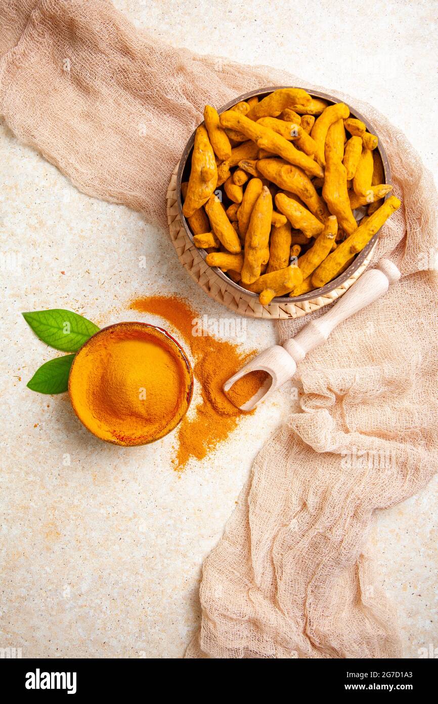 Dried turmeric roots and powder with leaves on a light background top ...