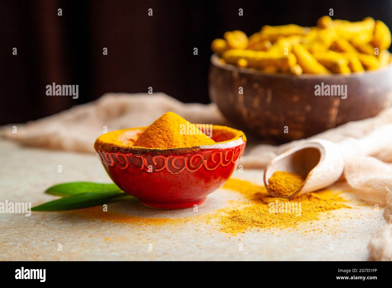 Dried turmeric powder with leaves and roots in coconut shell bowl Stock ...