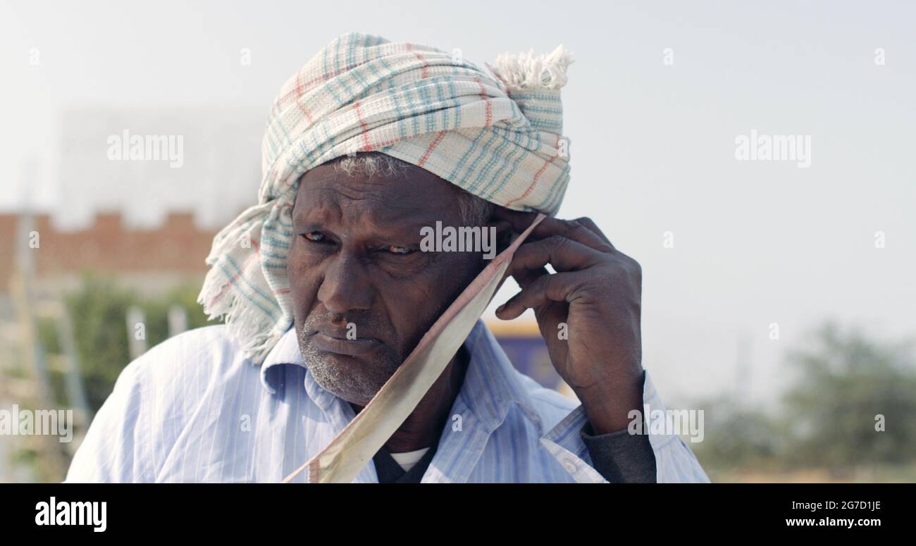 Closeup of an old Indian man taking off a Covid face mask while wearing ...