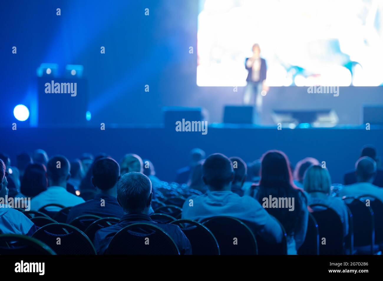 Audience listening to speaker in neon light Stock Photo - Alamy