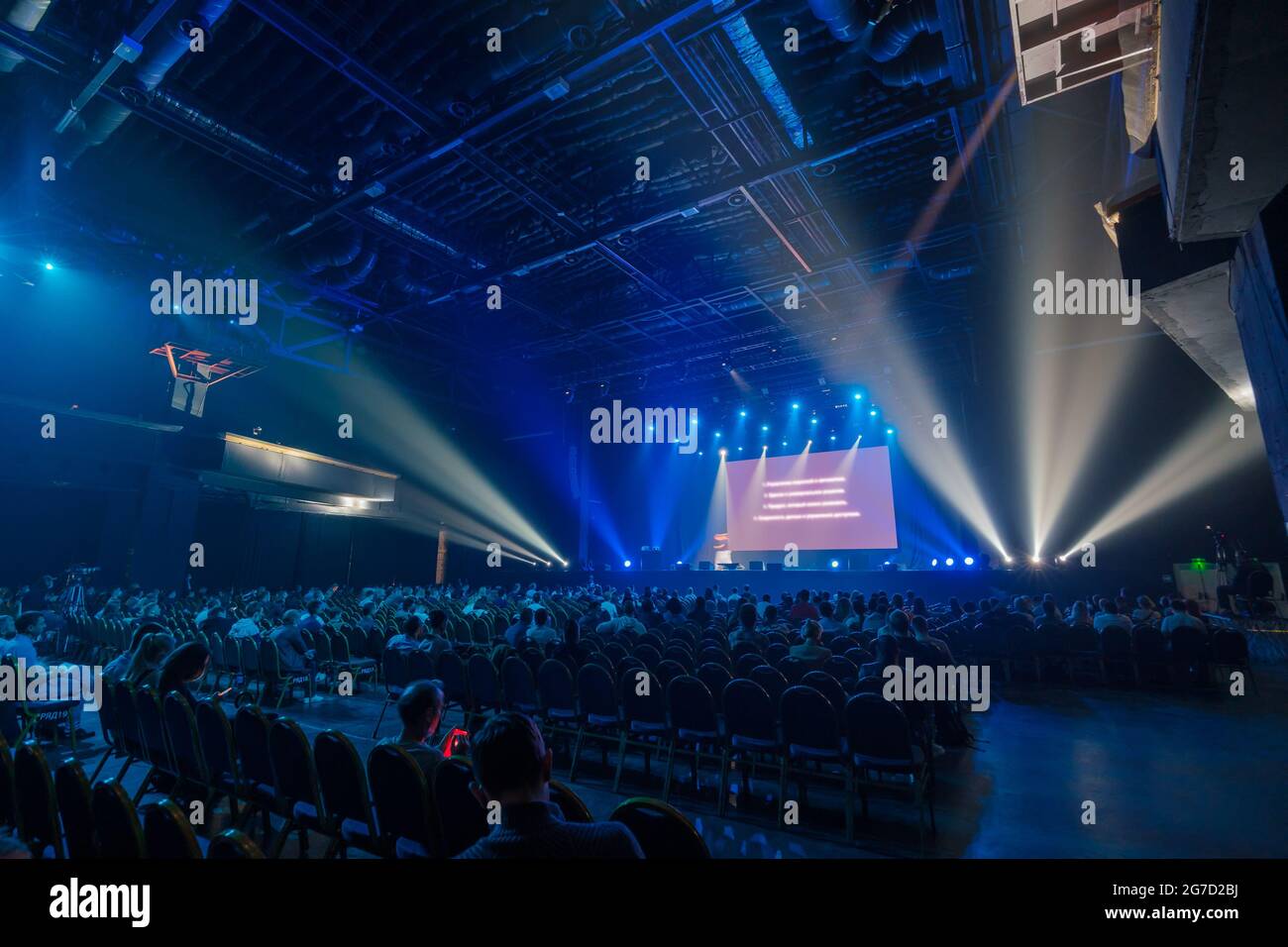 Audience sitting in front of stage with screen Stock Photo - Alamy