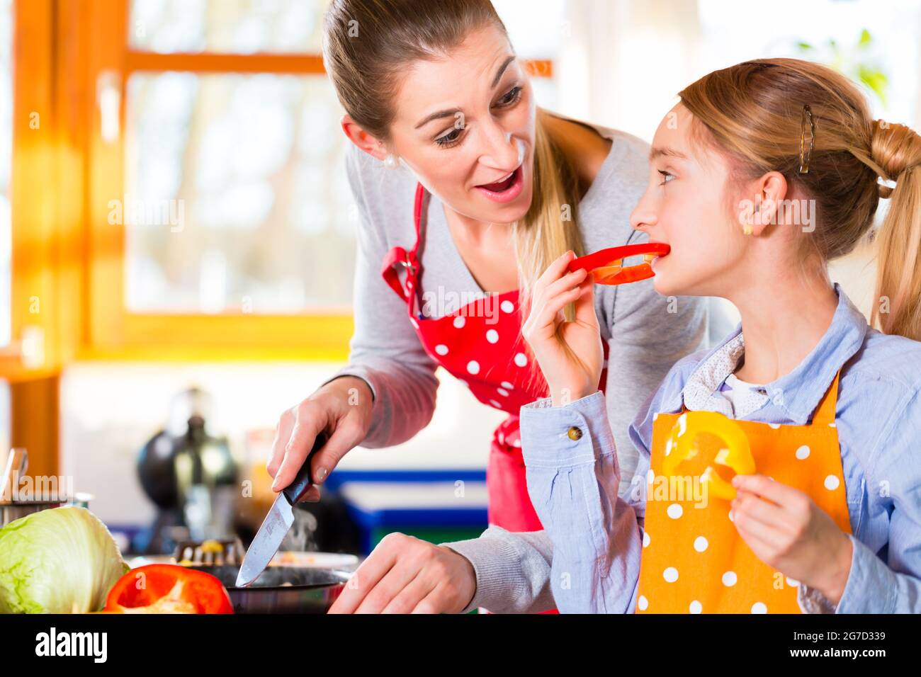 Mother and daughter cooking in domestic kitchen having fun together ...