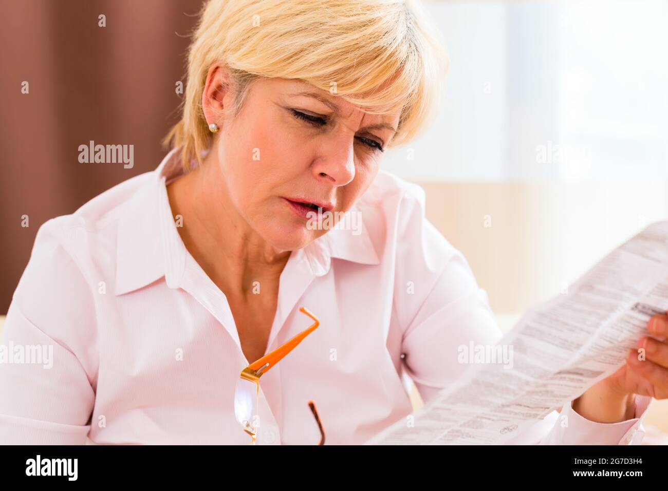 Old woman reading medicament package insert at home with glasses Stock ...
