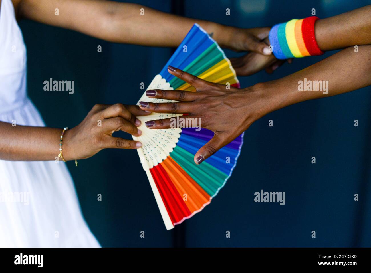 Hands hold LGBTQ pride fan and wristband Stock Photo - Alamy