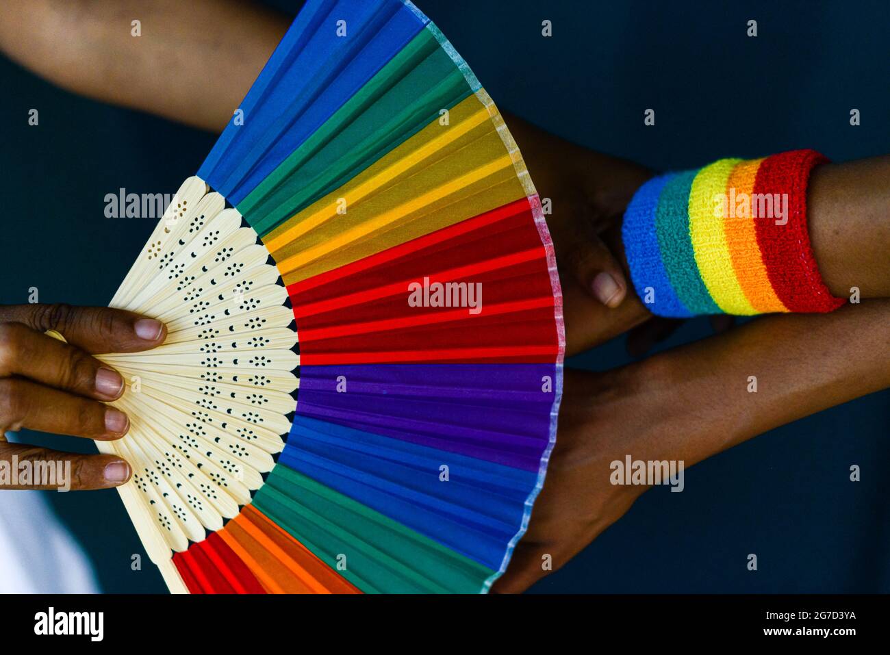 Hands hold LGBTQ pride fan and wristband Stock Photo - Alamy