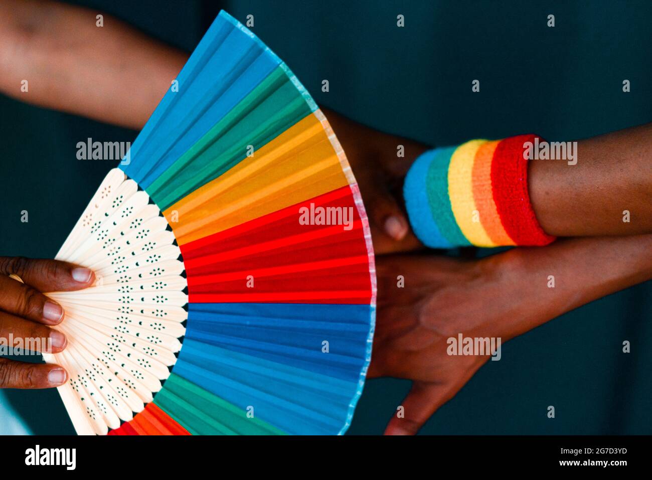 Hands hold LGBTQ pride fan and wristband Stock Photo - Alamy