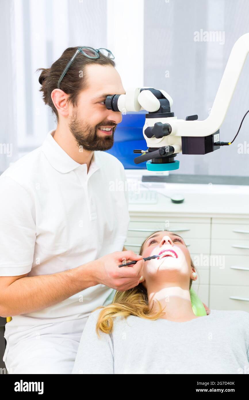 Dentist using microscope to check teeth of patient Stock Photo - Alamy