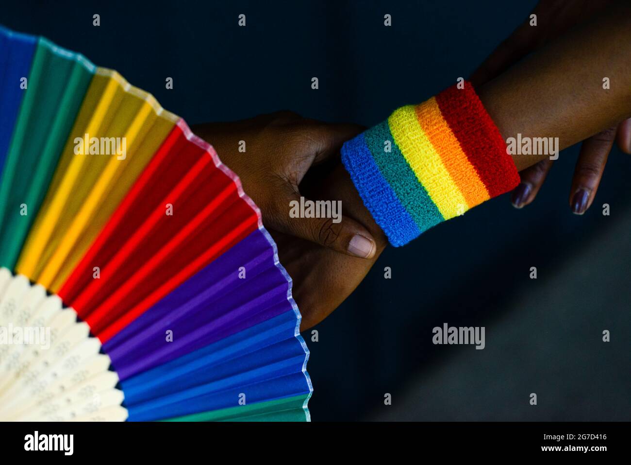 Hands hold LGBTQ pride fan and wristband Stock Photo - Alamy