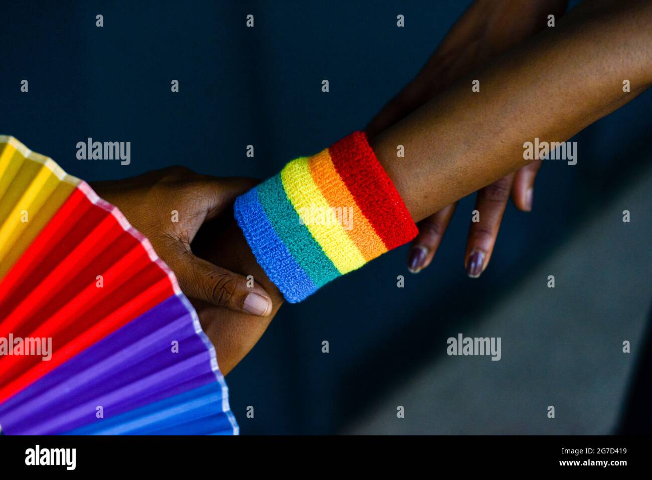 Hands hold LGBTQ pride fan and wristband Stock Photo - Alamy