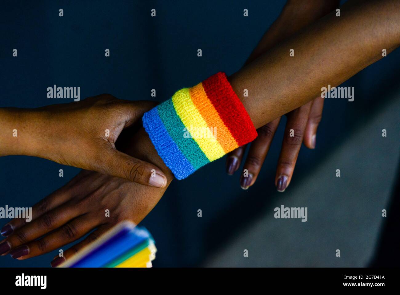 Hands hold LGBTQ pride fan and wristband Stock Photo - Alamy
