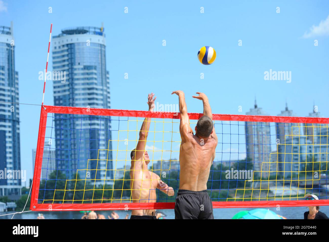 Beach volleyball. Male volley player hitting over the net attacking ...