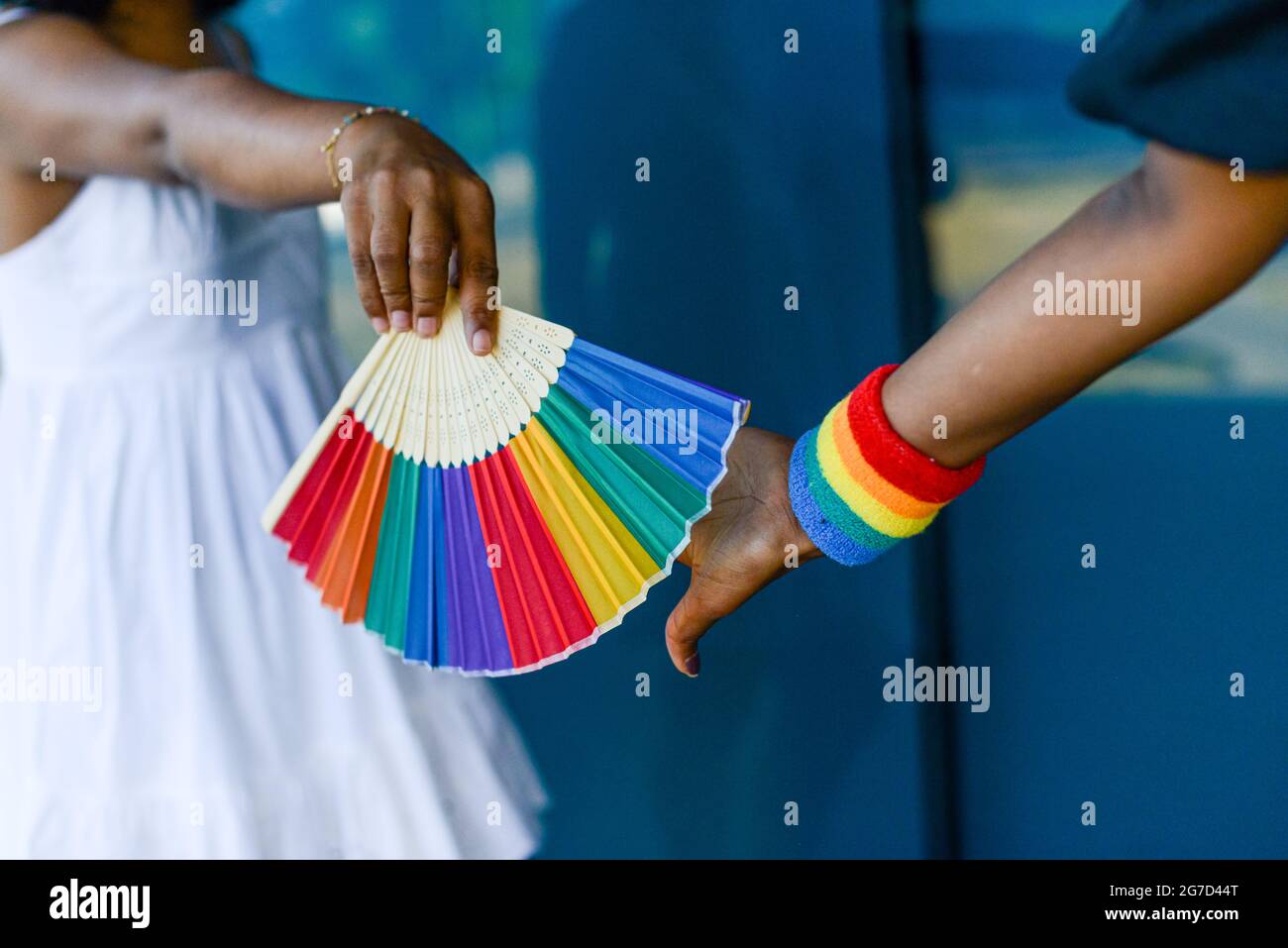 Human hands hold LGBTQ pride fan and wristband Stock Photo - Alamy