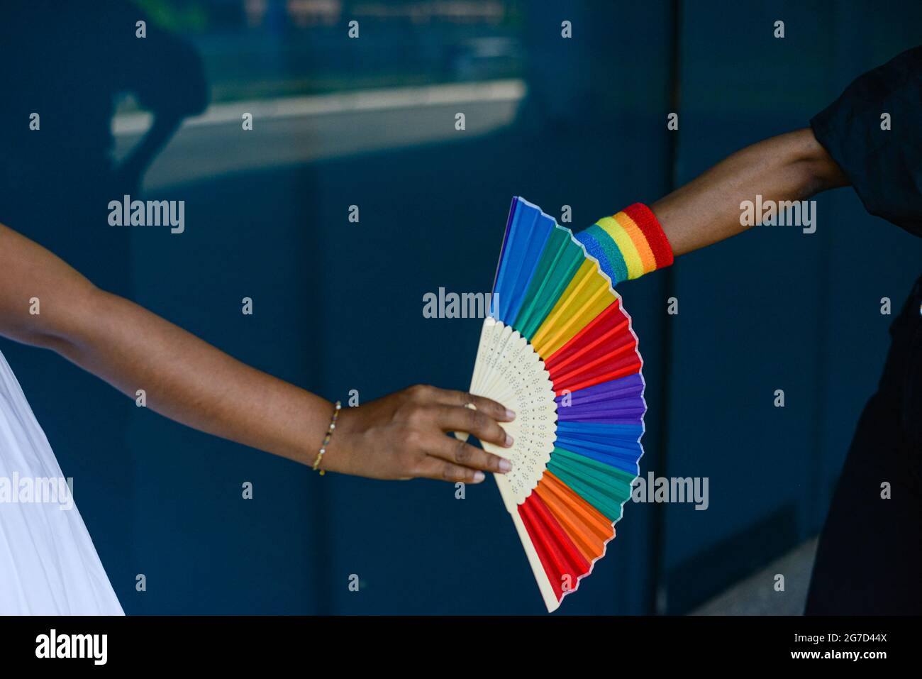 Human hands hold LGBTQ pride fan and wristband Stock Photo - Alamy