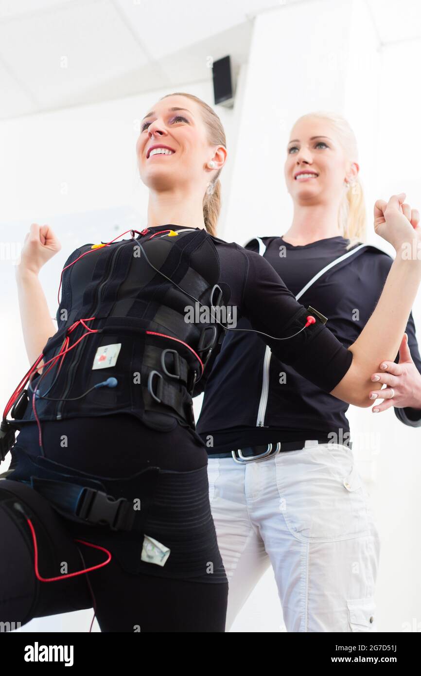 Female personal trainer giving man ems electro muscular stimulation ...