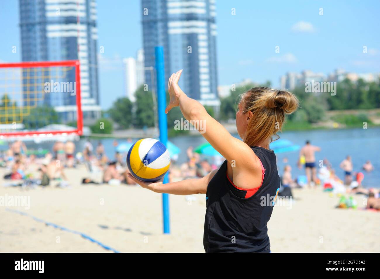 Beach volleyball. Female volley player serving the ball in front of the ...