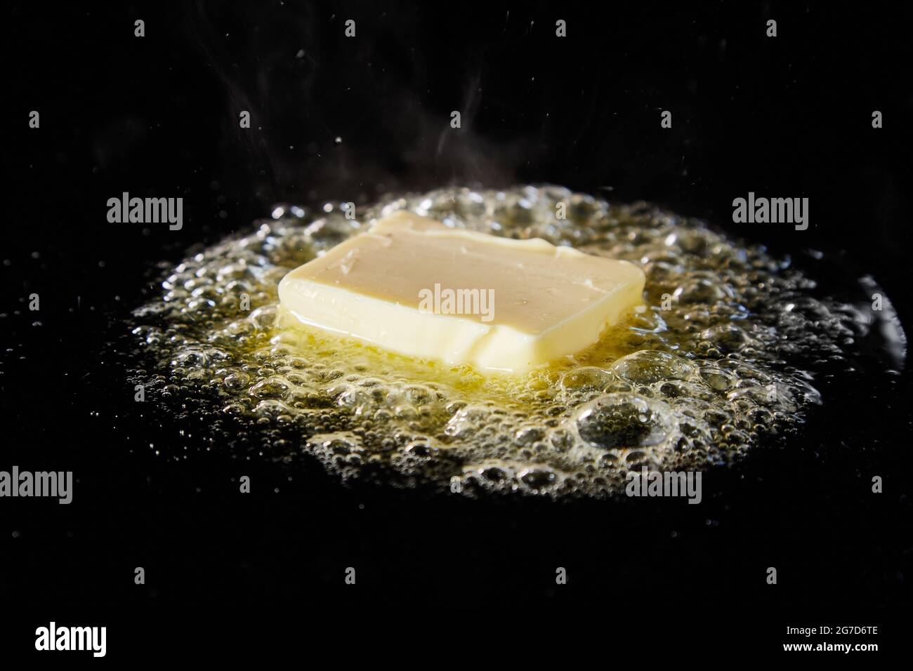 High angle of melting butter with steam on hot stove during cooking ...