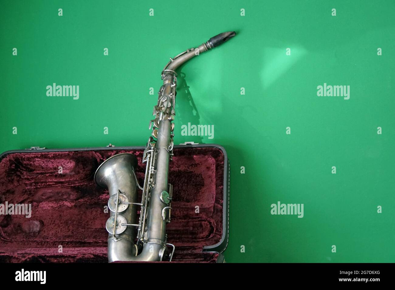 Old saxophone leaned on a green wall Stock Photo - Alamy