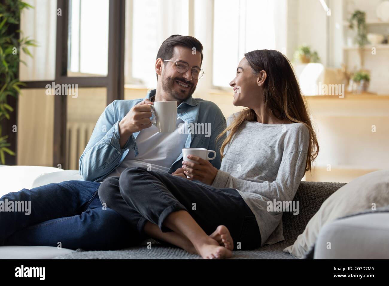 Calm relaxed couple holding cups rest on comfy sofa Stock Photo - Alamy