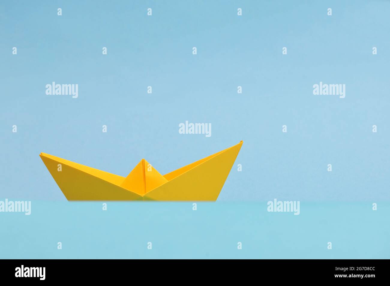 Conceptual Yellow Paper boat On Blue Background Stock Photo - Alamy