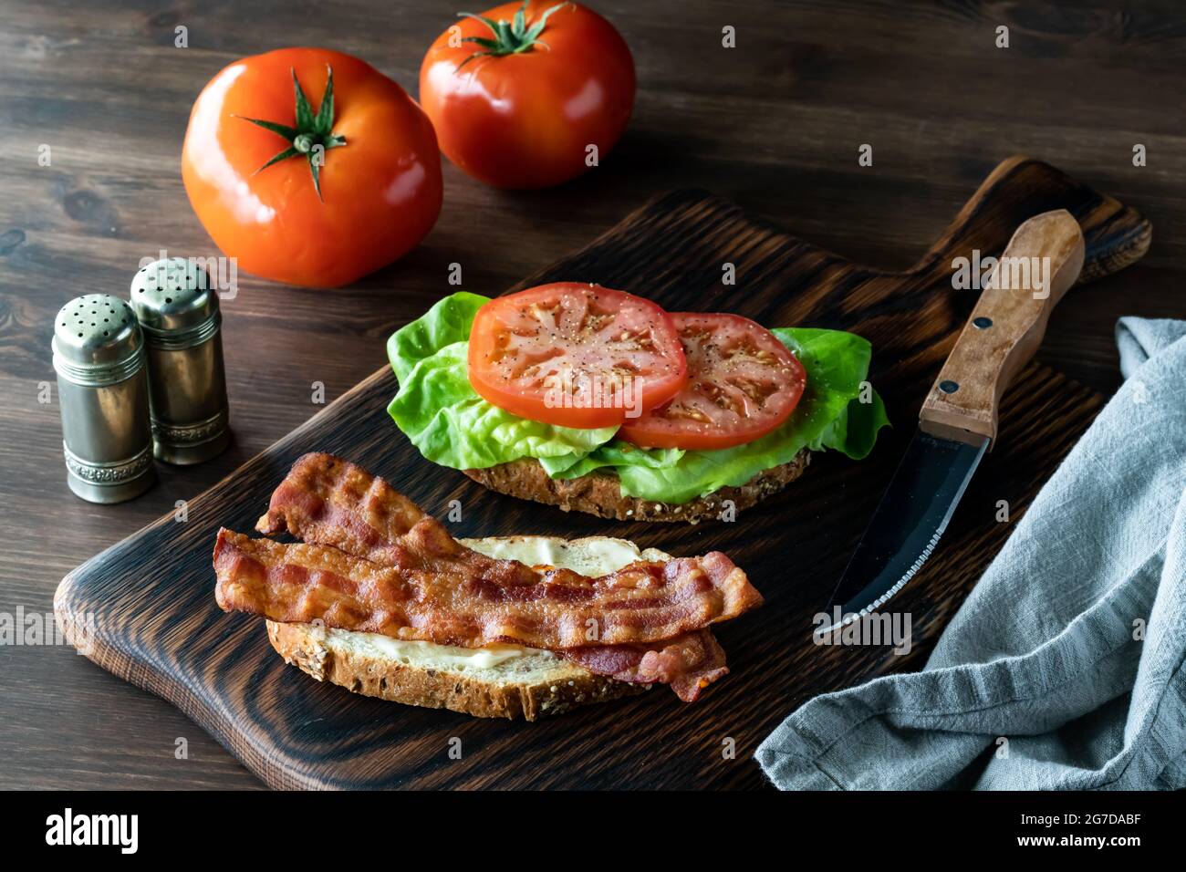 Open faced bacon and tomato sandwich on a wooden board, ready for ...