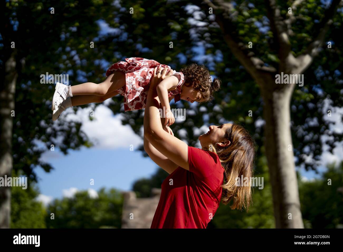 Mother throwing his daughter up while having a nice family time in a ...