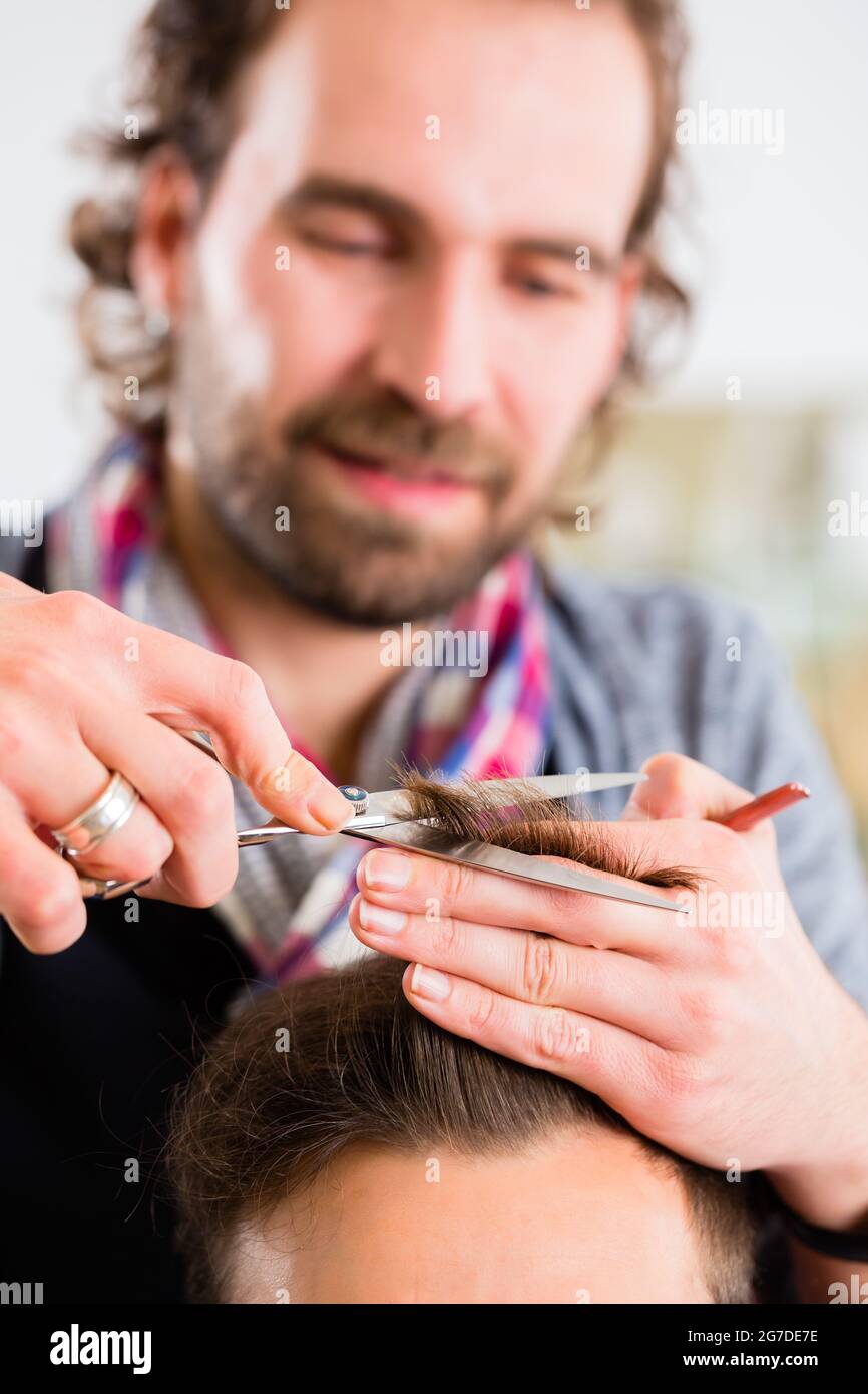 Barber trimming man hair in haircutter shop Stock Photo - Alamy