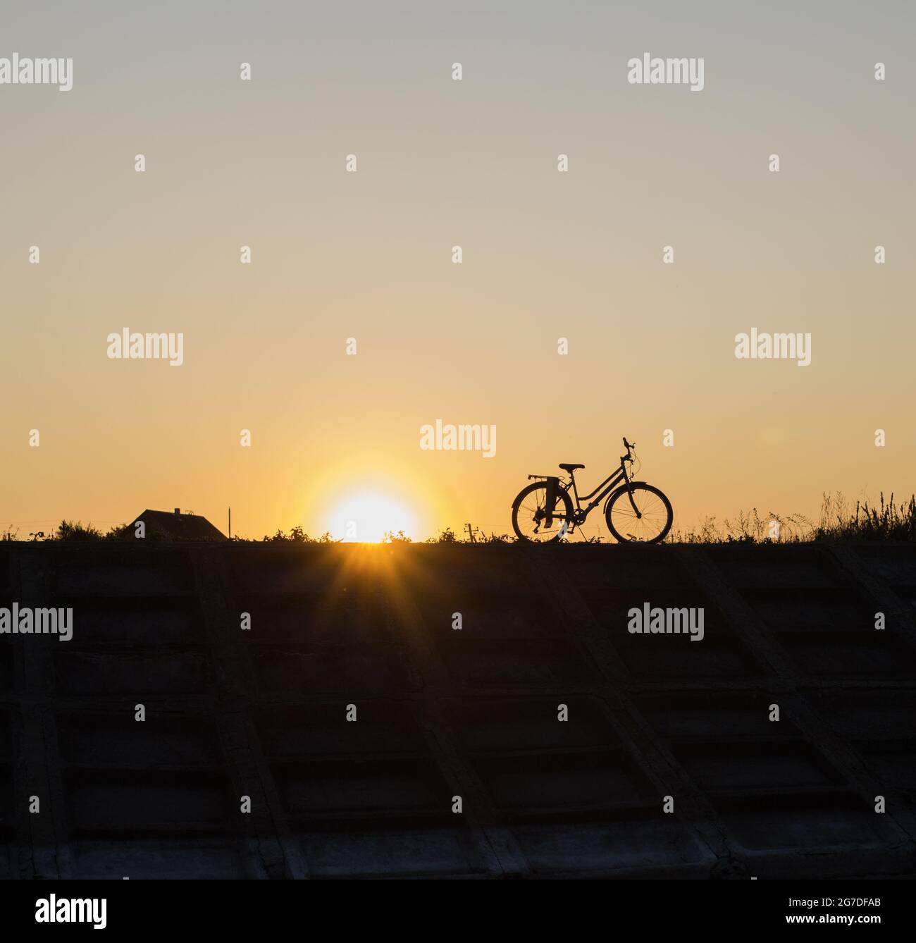 bicycle against the backdrop of yellow sunset sky and the setting sun ...