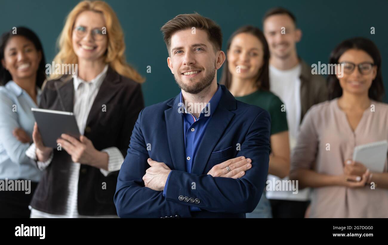 Happy male business leader posing with team in blurred background Stock ...