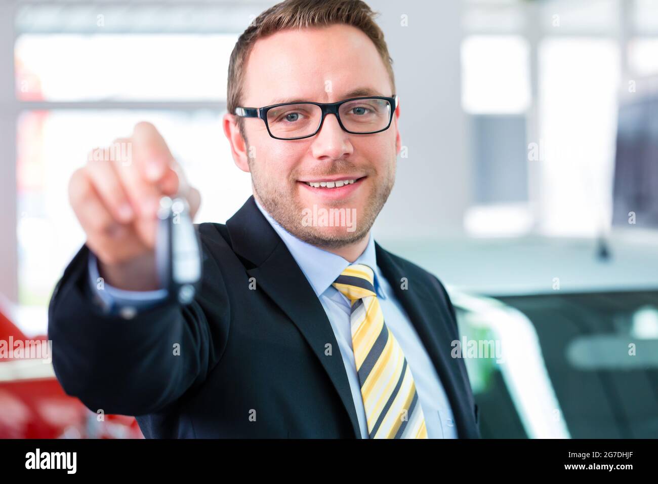 Salesman handing over auto key at car dealership Stock Photo - Alamy