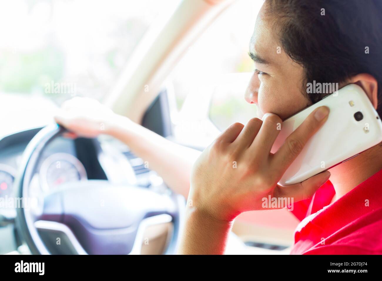 Asian young man telephoning with mobile phone or smartphone while ...