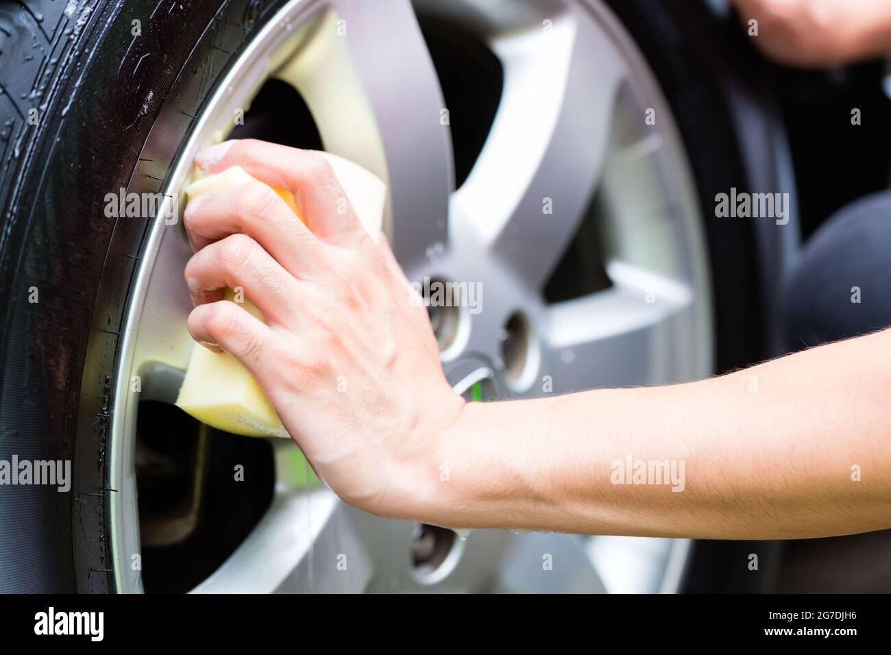 man cleaning wheel rim while car wash Stock Photo - Alamy