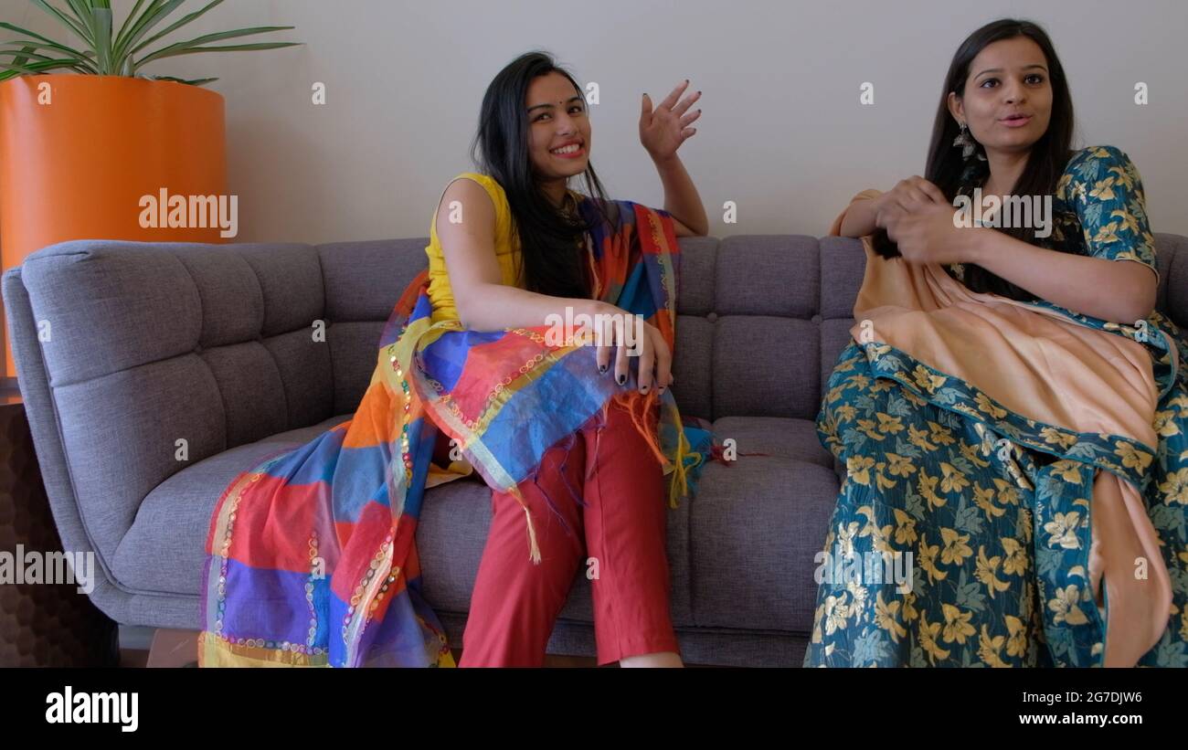 Beautiful South Asian woman sitting with her friend on a couch, both ...