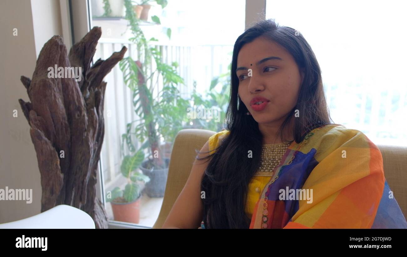 Closeup of a young Indian woman sitting down and talking while wearing ...