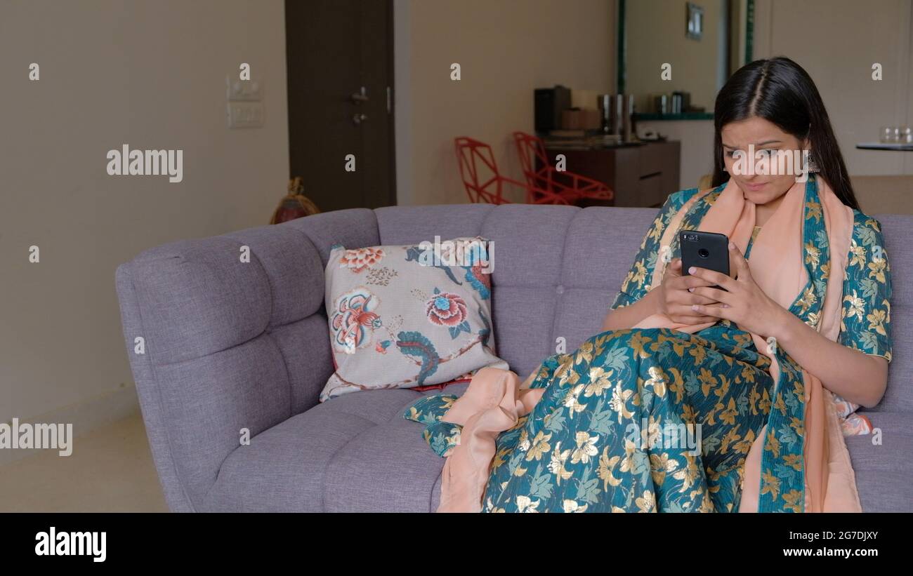 Young South Asian woman in traditional clothing sitting on a purple ...