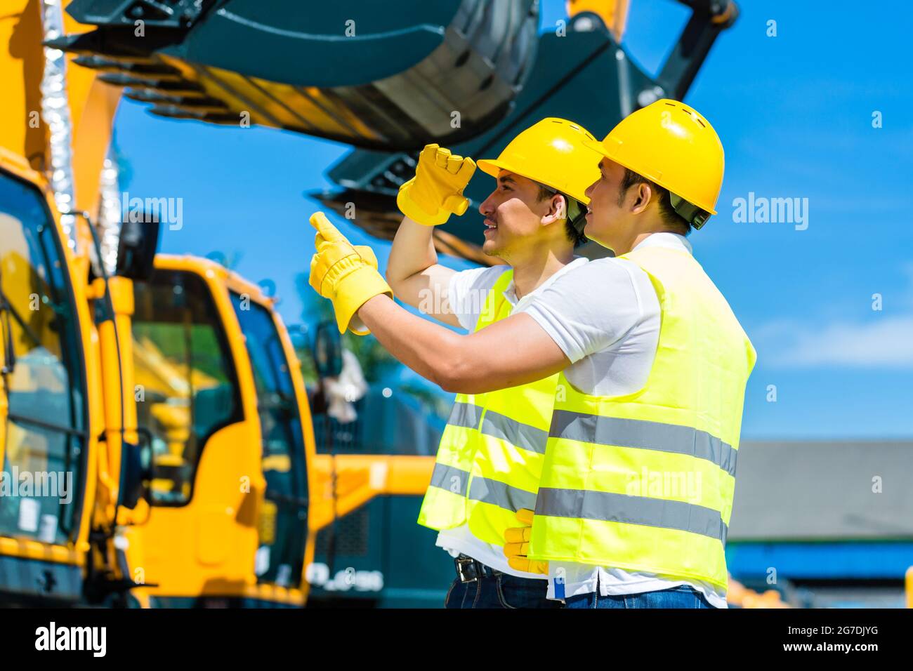 Asian worker at construction machinery of construction site or mining ...